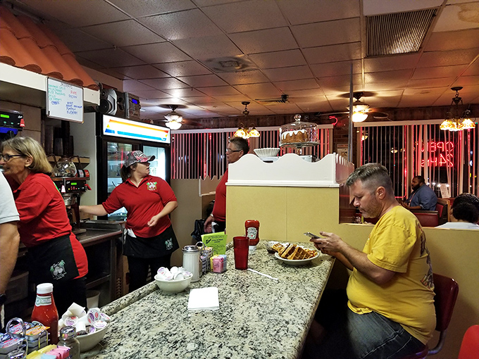 Inside, the bustling counter area hums with activity as servers in red shirts navigate the classic diner space with practiced efficiency. 