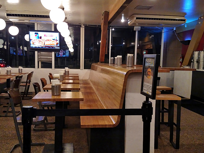 Inside The Oinkster, warm wood tones and globe lighting create the perfect backdrop for the serious sandwich business about to unfold.