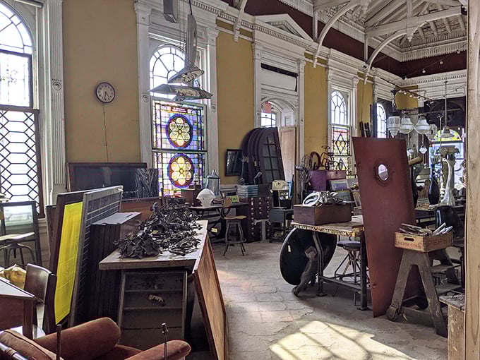 Sunlight streams through stained glass windows, illuminating a wonderland of salvaged treasures where every corner tells a different architectural story.