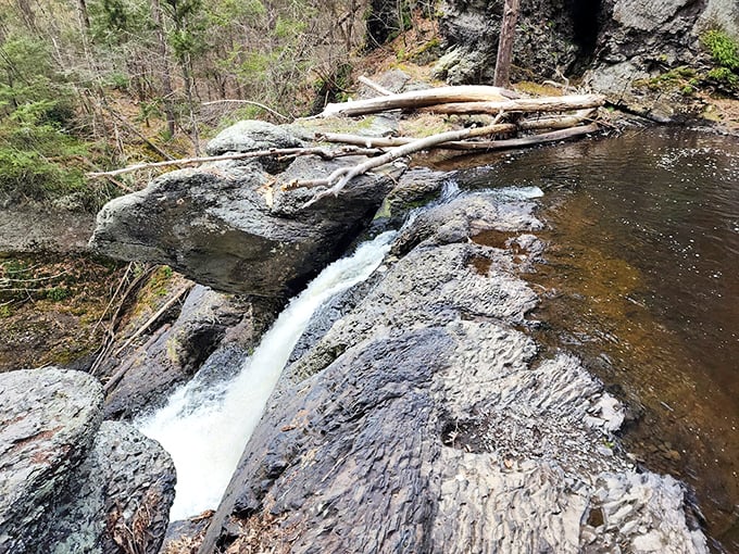 The upper cascade creates a perfect postcard moment as water dances over smooth stone, sculpted by centuries of persistent flow.