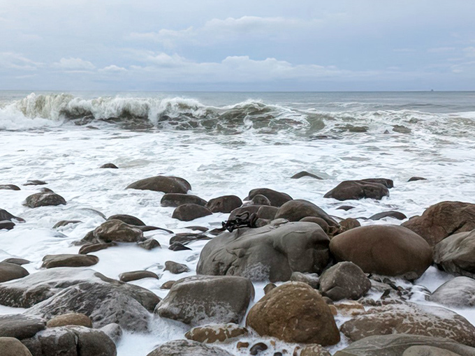 Nature's mosaic of smooth stones meets frothy waves in a timeless dance. The Pacific doesn't just crash here&mdash;it converses with the ancient coastline.