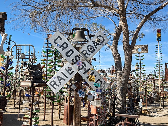 This weathered railroad crossing sign stands sentinel among the bottle trees, a nostalgic reminder of America's rail-riding past.