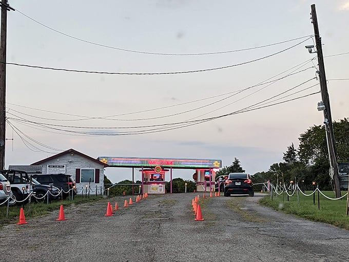 The neon-trimmed entrance beckons like a portal to simpler times, when entertainment came with fresh air and starlight.