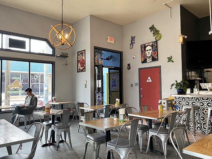 Inside, modern industrial meets Mexican charm with colorful Frida Kahlo artwork, metal chairs, and wooden tables creating the perfect backdrop for taco nirvana.