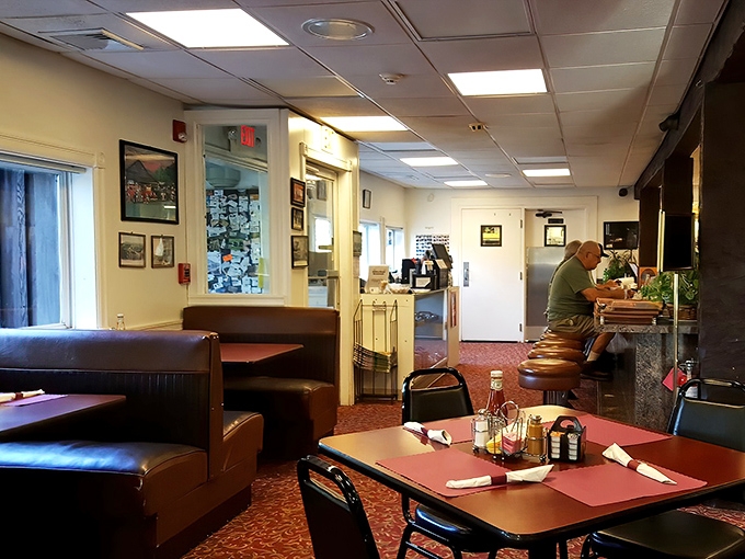 Inside, classic diner comfort awaits with burgundy booths and counter seating where regulars perch, coffee mugs in hand, trading stories between bites.