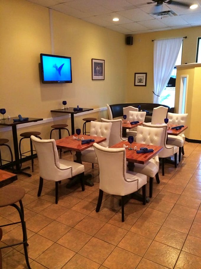 Elegant white chairs and blue napkins create an intimate dining space where seafood dreams come true without pretension.