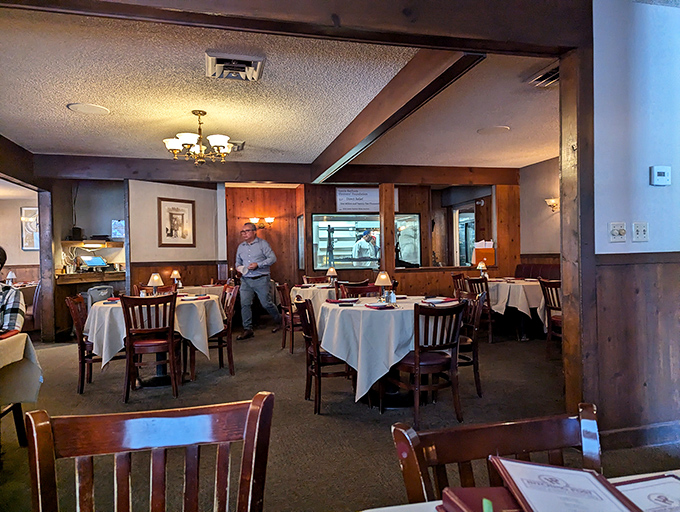 Step inside to a world where white tablecloths meet wood-paneled warmth. This dining room has hosted more memorable meals than most family kitchens.