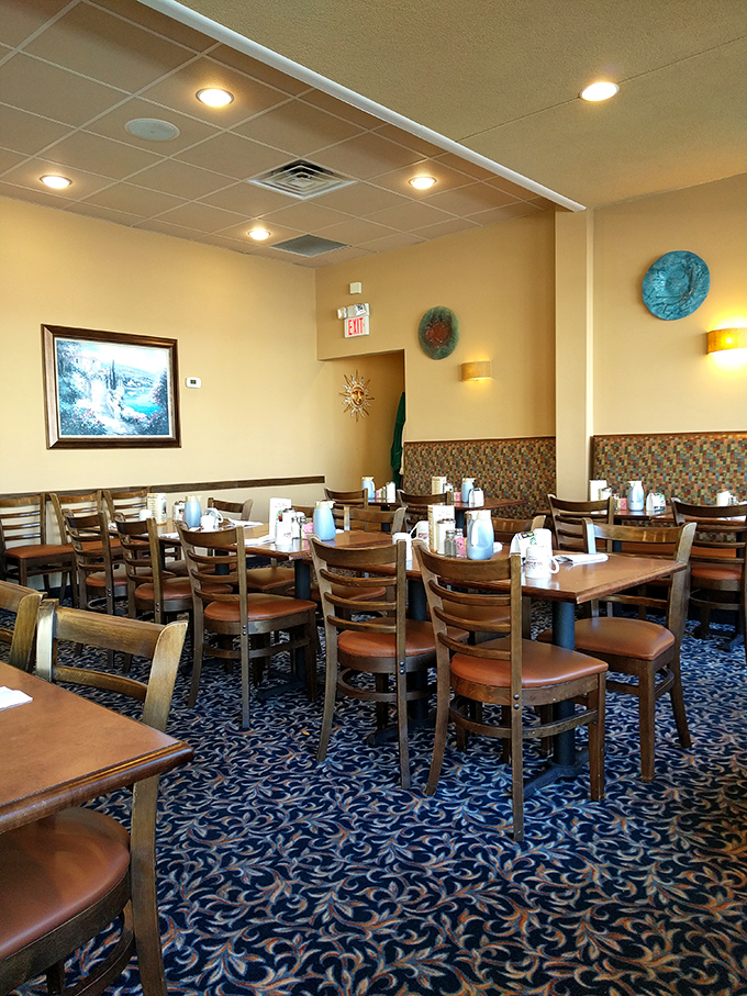 Simple wooden chairs, patterned booths, and decorative plates create an atmosphere that whispers, "We're focusing on your food, not winning design awards."