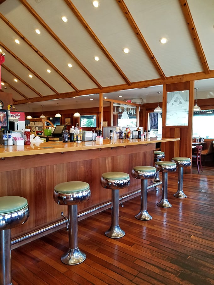Classic diner counter seating with mint-green stools invites solo diners to perch and watch the breakfast ballet unfold in this wood-paneled sanctuary.