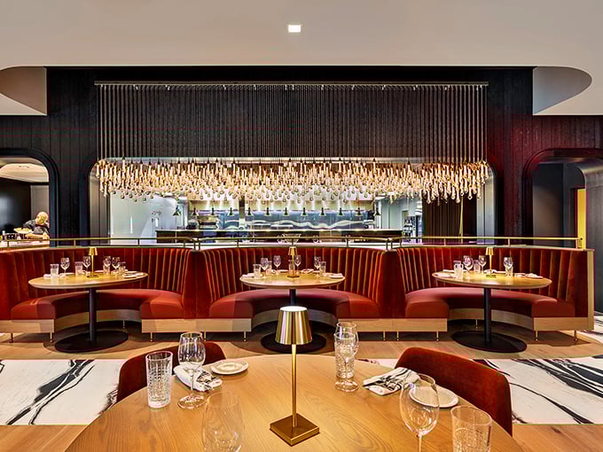 Dramatic lighting meets plush red velvet in Fahrenheit's dining room, where that stunning chandelier installation practically whispers "special occasion."