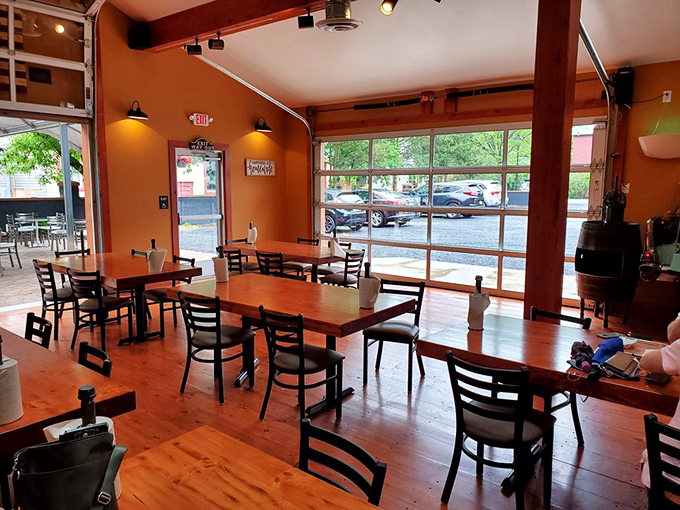 Sunlight floods through large windows into a warm, orange-walled dining room where wooden tables stand ready for the smoky feast to come.