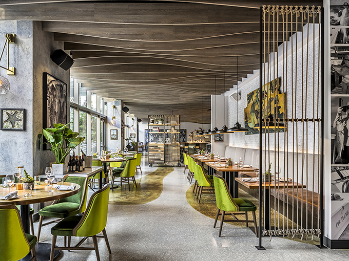 Lime green chairs pop against wave-inspired ceilings, creating a space that's equal parts sophisticated and playful. Ocean vibes without getting your feet wet.