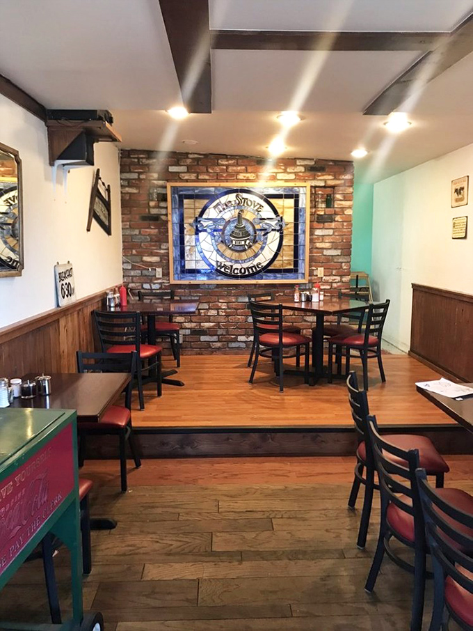 That stained glass welcome sign against exposed brick isn't just decor&mdash;it's a promise of the homestyle comfort awaiting at your red-cushioned table.