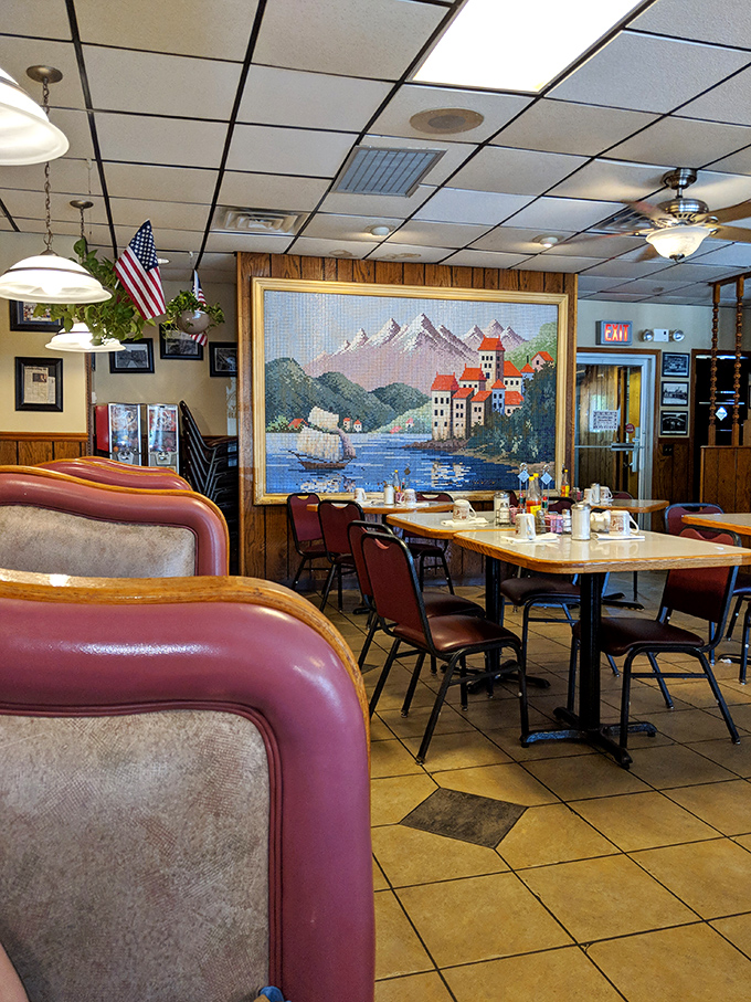 Inside Ray's, burgundy booths frame a dining room where that magnificent tapestry isn't just decoration—it's a promise that some experiences transcend the ordinary.