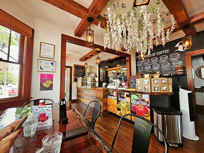 Wooden beams and hanging floral decorations create a space that's equal parts enchanted garden and cozy living room. Coffee paradise found!