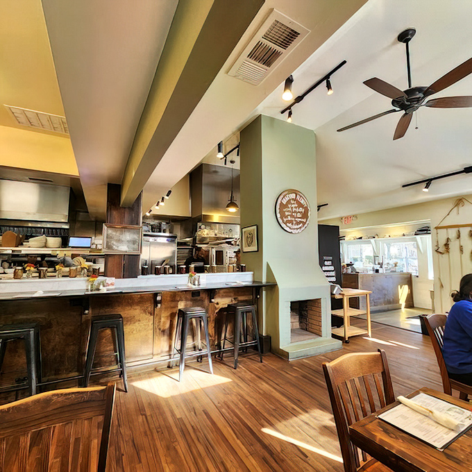 Warm wooden floors, soft green accents, and an open kitchen create that rare atmosphere where you instantly feel like a regular.