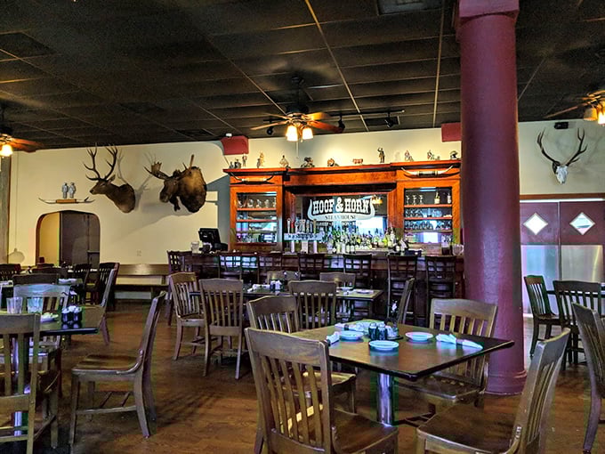 Trophy mounts keep watchful eyes over diners as the warm, rustic interior balances hunting lodge charm with steakhouse sophistication.