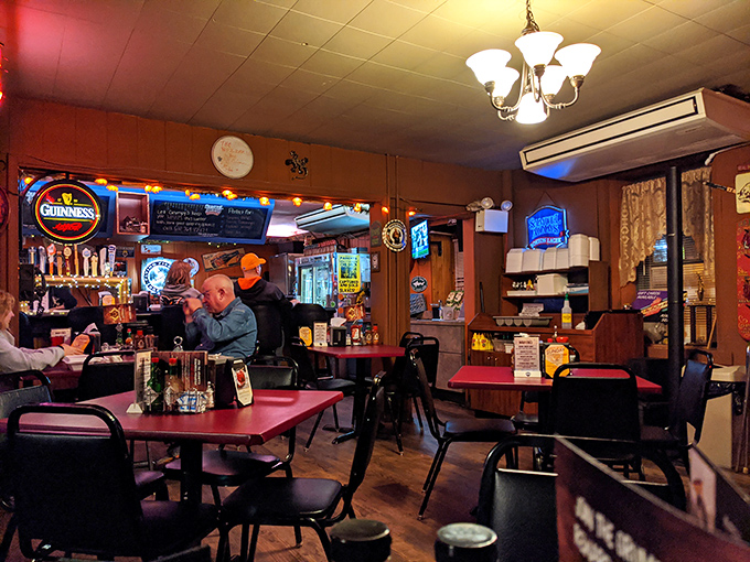Inside, neon beer signs cast a warm glow over red tables where strangers become friends, united by the universal language of great barbecue.