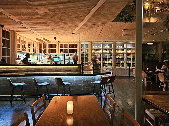 The warm wooden ceiling and subway-tiled bar create that rare atmosphere where you feel instantly at home, yet somehow cooler than you were outside.