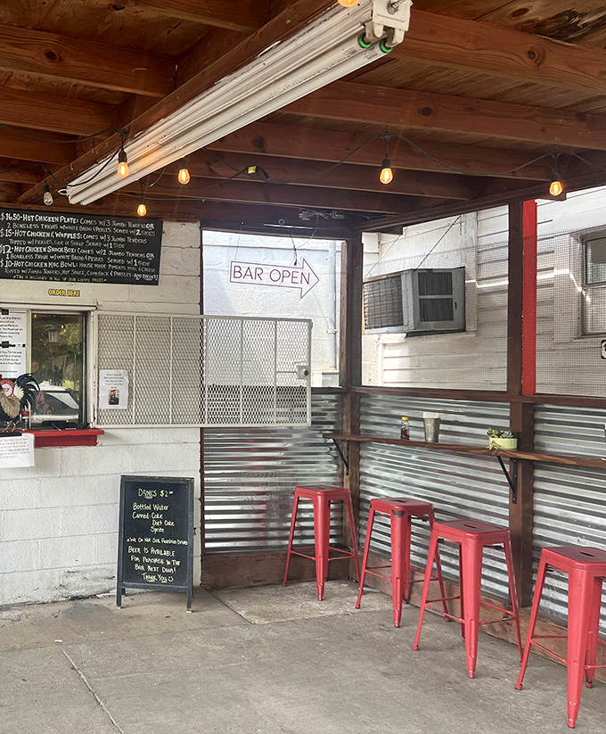 Simple red stools and corrugated metal walls create the perfect no-frills backdrop for a serious hot chicken experience. The "Bar Open" sign signals sweet relief for brave spice adventurers.