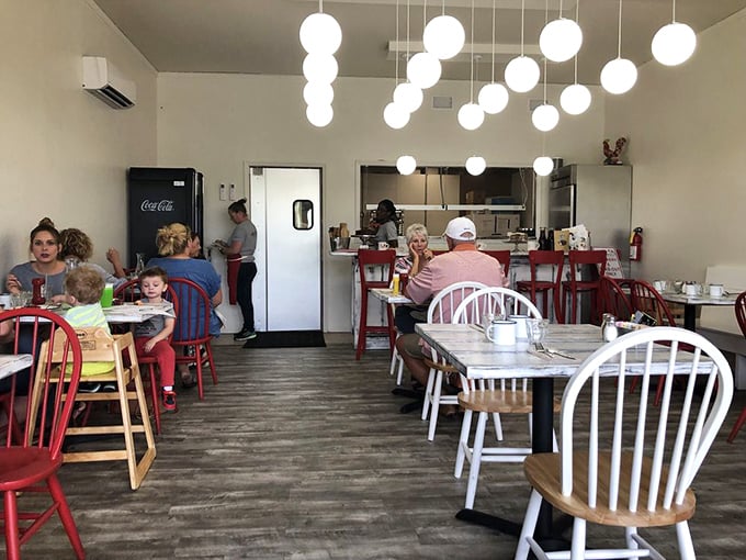 Inside, globe pendant lights cast a warm glow over red and white chairs. The open, airy space feels like the breakfast nook you've always dreamed about.