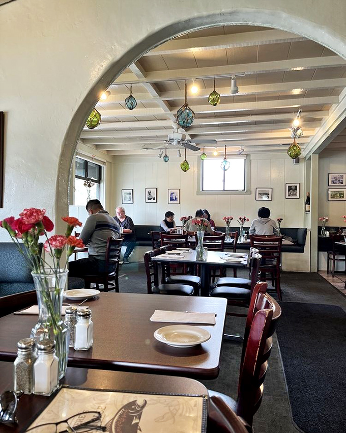 Colorful glass fixtures hang from white beams, creating that perfect balance of "nice enough for a special occasion, casual enough for Tuesday night."