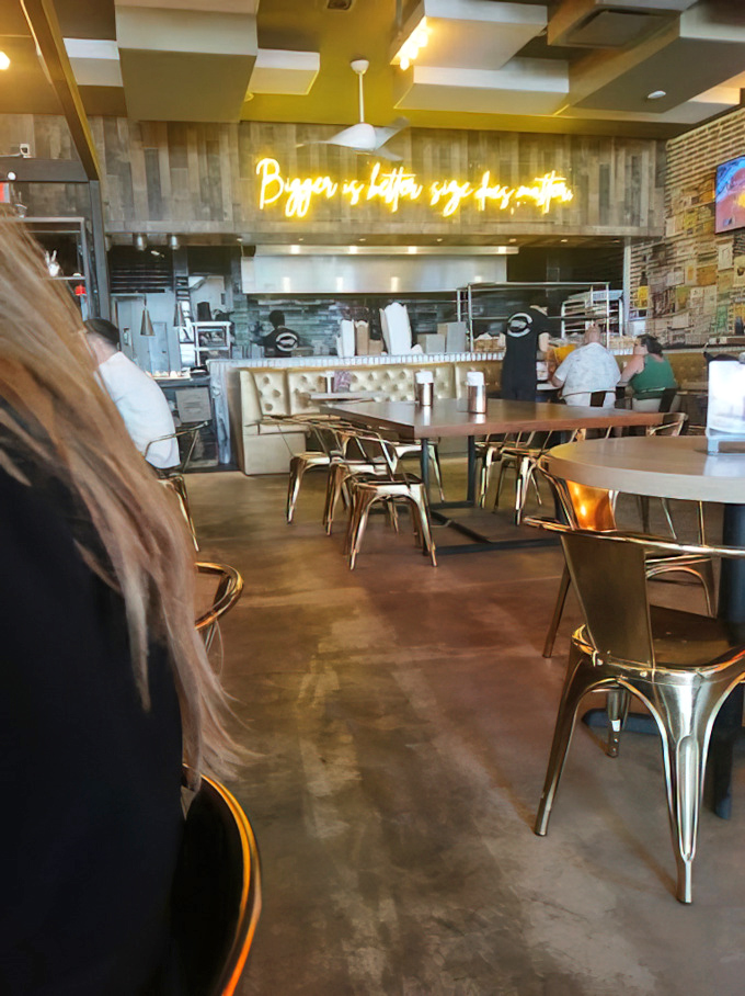 "Bigger is better, size does matter" proclaims the neon truth overhead, while gold-toned chairs await burger pilgrims in this temple of beef.