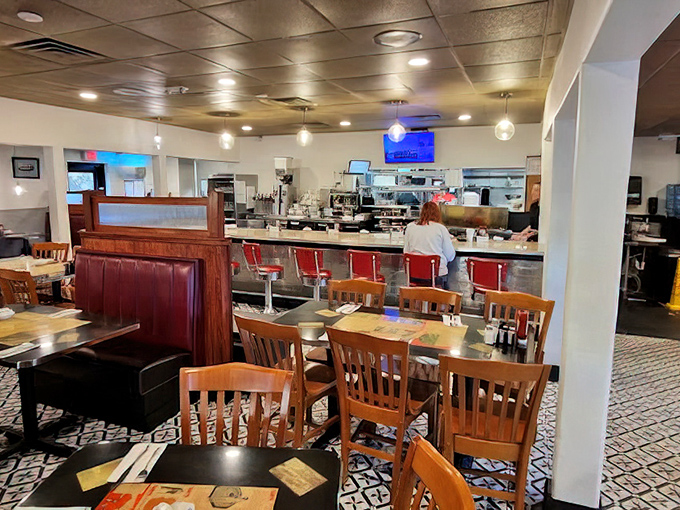 Classic diner ambiance meets modern comfort with wooden chairs, cozy booths, and those iconic red counter stools that practically whisper "sit here, stay awhile."