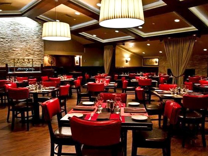 Red chairs pop against warm wood tones, creating a dining room that says "special occasion" without whispering "mortgage payment required."