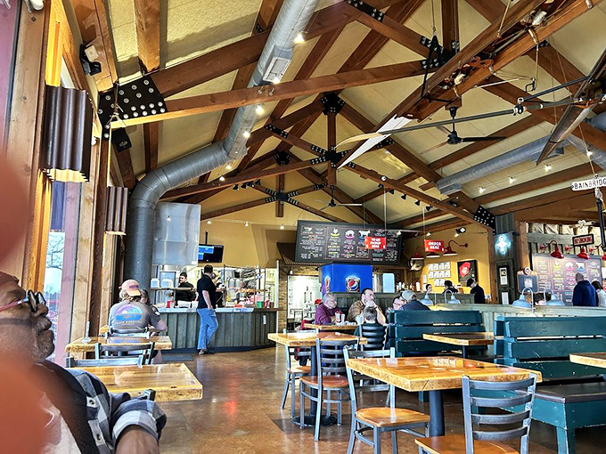 Exposed wooden beams stretch across the ceiling like the ribcage of some magnificent beast, creating an atmosphere as warm as the smokers out back.