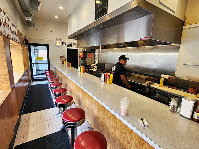 A symphony of sizzles and spatula clangs plays from behind the counter, where culinary magic happens just inches from your red vinyl perch.
