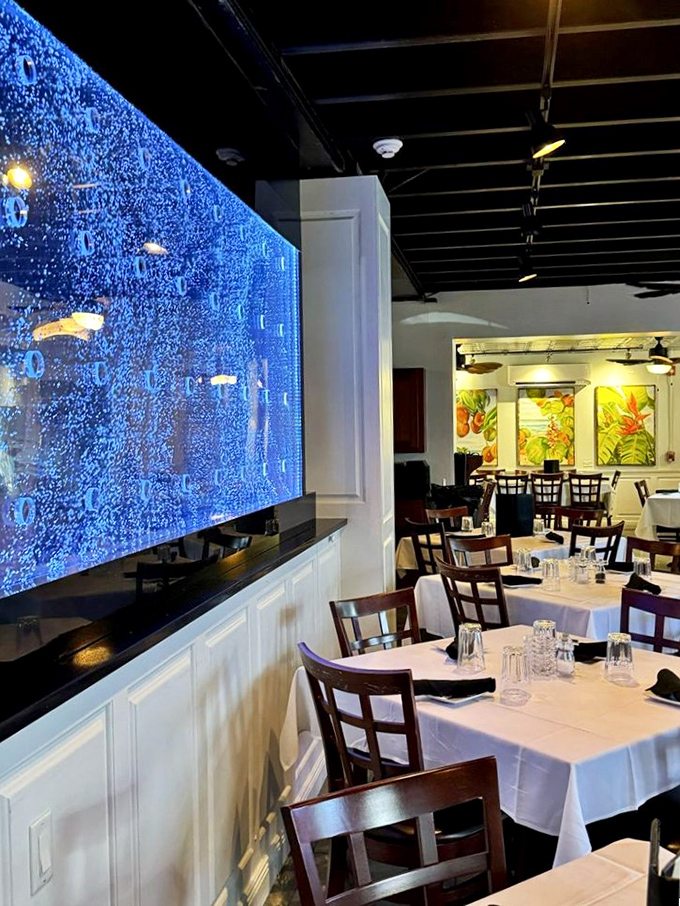 The bubbling blue aquarium wall transforms dinner into an underwater fantasy. White tablecloths meet marine magic in this elegant yet approachable dining room.