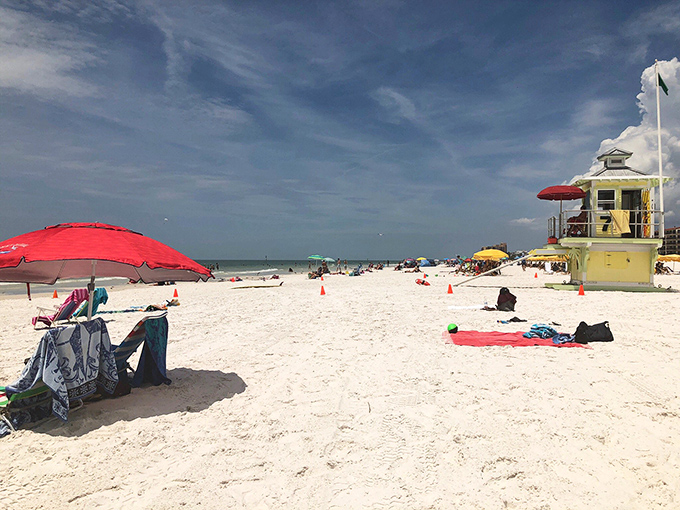 Beach guardians keep watch from their sunny perches, ensuring your only worry is whether to swim now or nap under that perfect red umbrella first.
