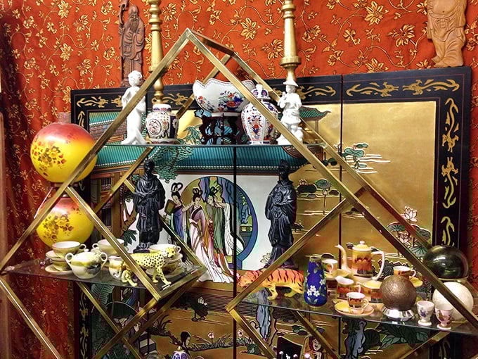 This delicate Asian-inspired display transforms ordinary shelving into an extraordinary cultural journey. The brass framework elegantly showcases porcelain treasures against rich crimson backdrops. 