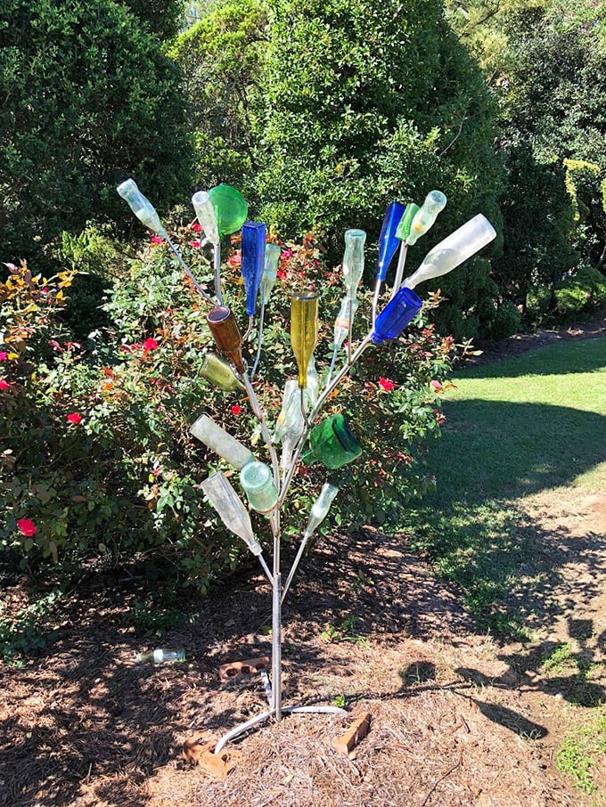 Southern folk art meets horticulture&mdash;this bottle tree captures sunlight in colored glass while surrounded by meticulously shaped greenery.