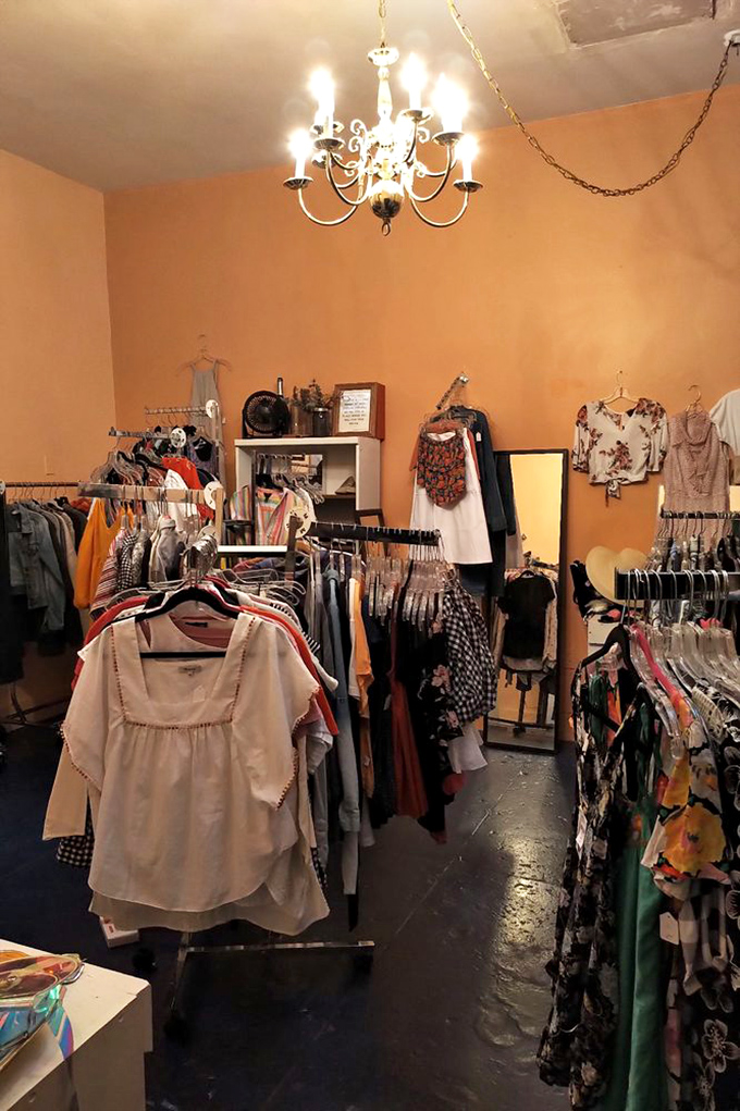 Under the warm glow of a vintage chandelier, racks of carefully curated clothing await their second chance at fashion stardom.
