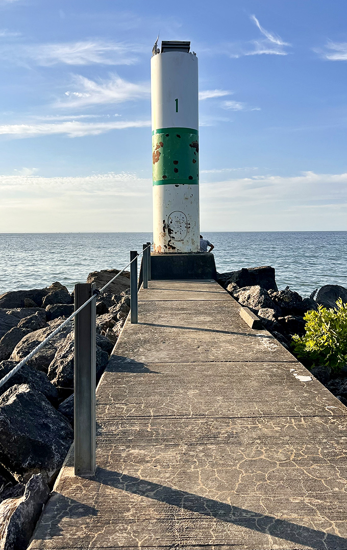 This stoic lighthouse stands guard where lake meets sky. A maritime sentinel that's seen more summer romances and fishing tales than a Hallmark movie marathon.