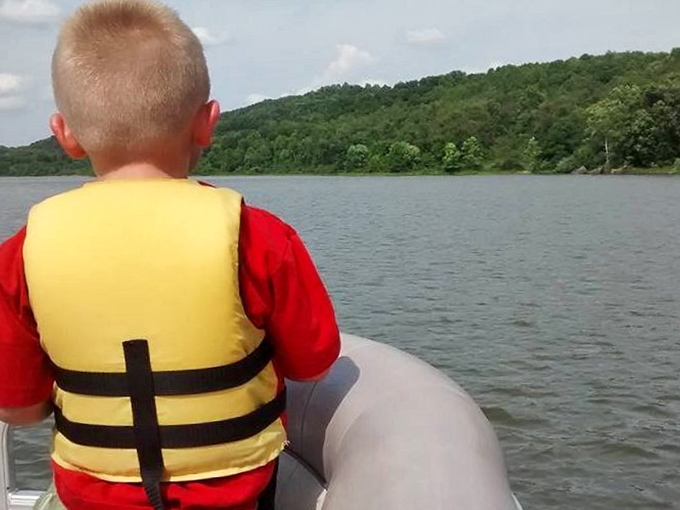 Adventure begins with a life vest and childlike wonder. This young explorer scans the horizon for treasures only visible from the water.