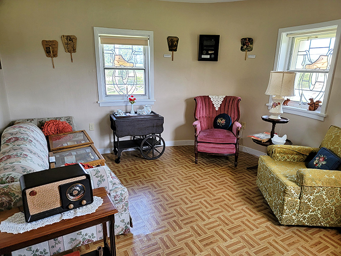 The living room blends vintage charm with shoe-themed decor. That pink armchair has probably heard some fascinating stories from bewildered first-time visitors.
