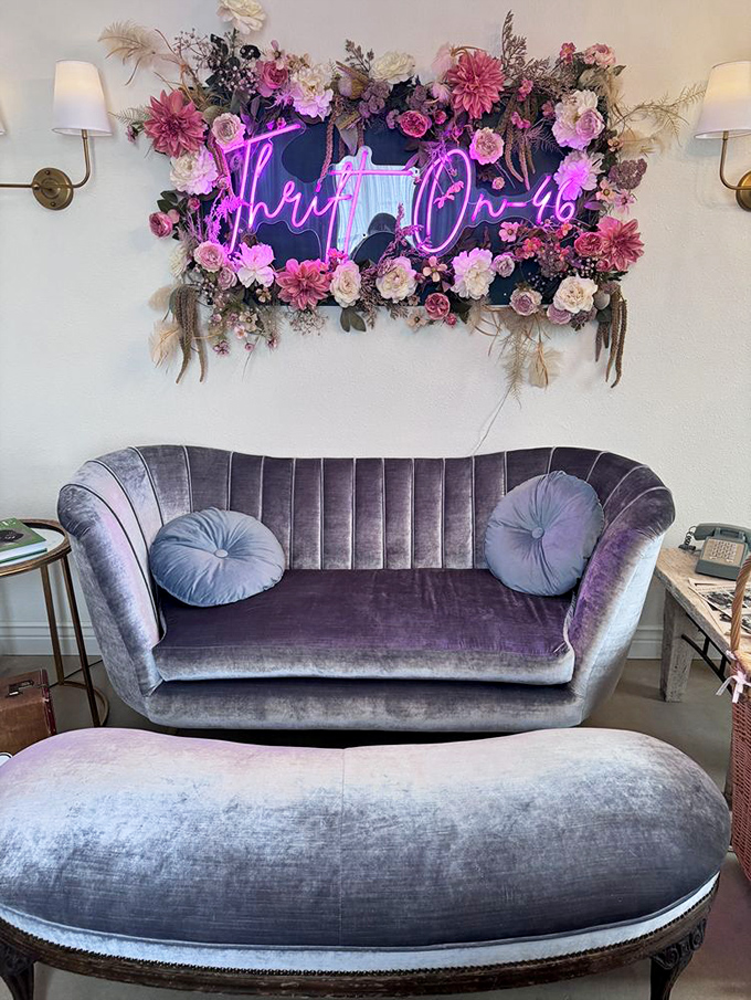 That purple velvet loveseat beneath the neon sign isn't just furniture—it's a throne for the newly crowned royalty of thrift store victories.