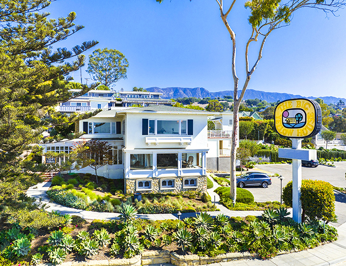 The Big Yellow House stands as a sunny landmark against the blue California sky, promising coastal cuisine with a side of ocean views.