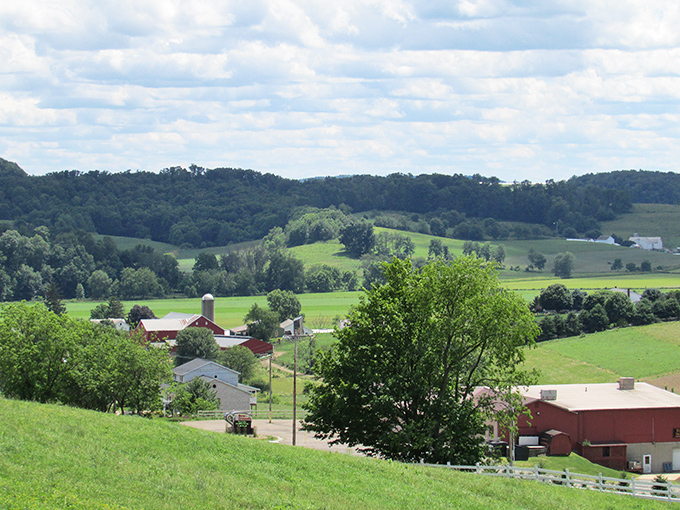 Rolling hills unfold like nature's screensaver, dotted with red barns and silos that have witnessed generations of sunrise to sunset rhythms. 