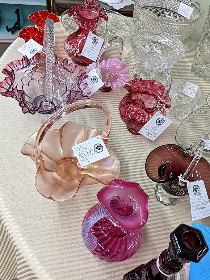 Delicate pink and ruby cranberry glass catches the light, each piece tagged with its history—silent storytellers from another era's dinner parties.