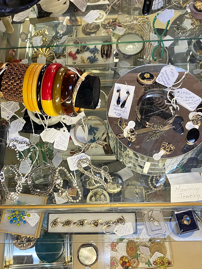 Bakelite bangles and mourning jewelry glitter under glass, each piece whispering stories from decades past to those who lean in close.