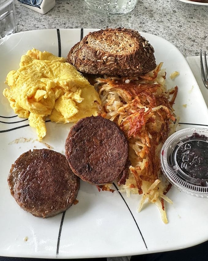 Breakfast perfection on a plate: fluffy scrambled eggs, crispy hash browns, and sausage patties that would make any morning person sing.
