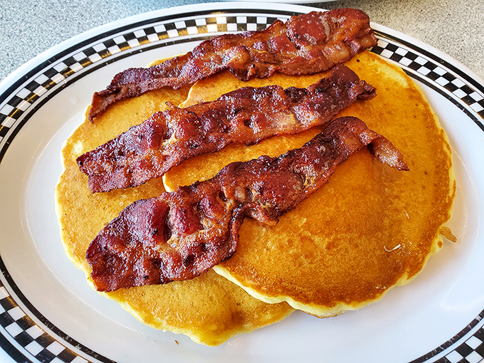 Golden pancakes supporting crispy bacon strips&mdash;a breakfast alliance so perfect it should have its own national holiday or at least a dedicated fan club.