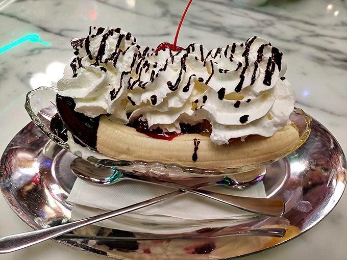 Behold the banana split in all its glory! Whipped cream mountains, chocolate drizzle valleys, and that cherry summit create a dessert landscape worth conquering.