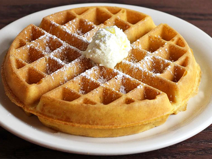 The Belgian waffle arrives like royalty &ndash; golden, crisp, and dusted with powdered sugar. That butter crown melts into every perfect pocket.