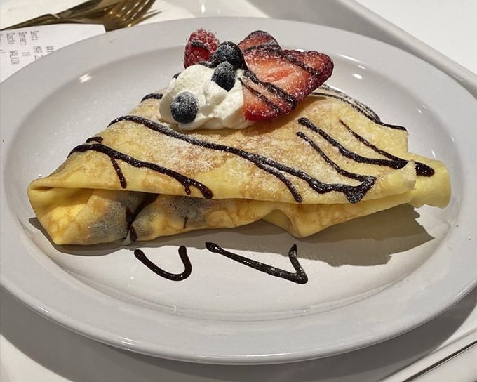 This isn't just a crepe—it's a delicate envelope delivering a love letter of fresh berries, whipped cream, and chocolate drizzle straight to your soul.