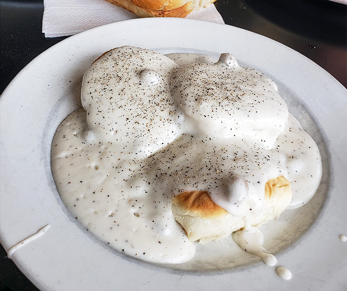 Behold the holy grail of comfort food! These biscuits disappear beneath a creamy avalanche of pepper-speckled gravy that would make your grandmother weep with joy.